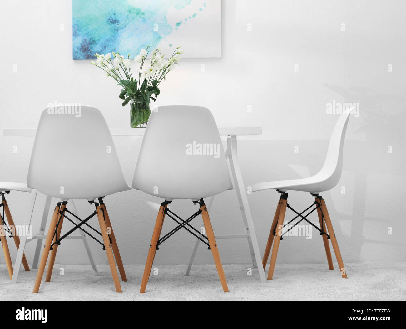 Modern dining room. White chairs and table with bouquet of flowers ...