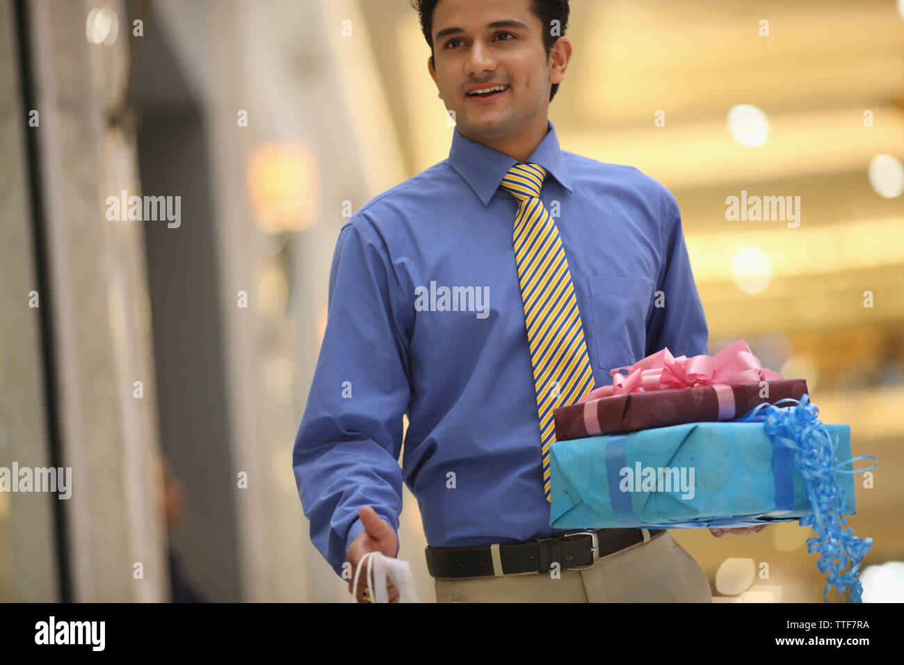Man holding gifts in a shopping mall Stock Photo - Alamy
