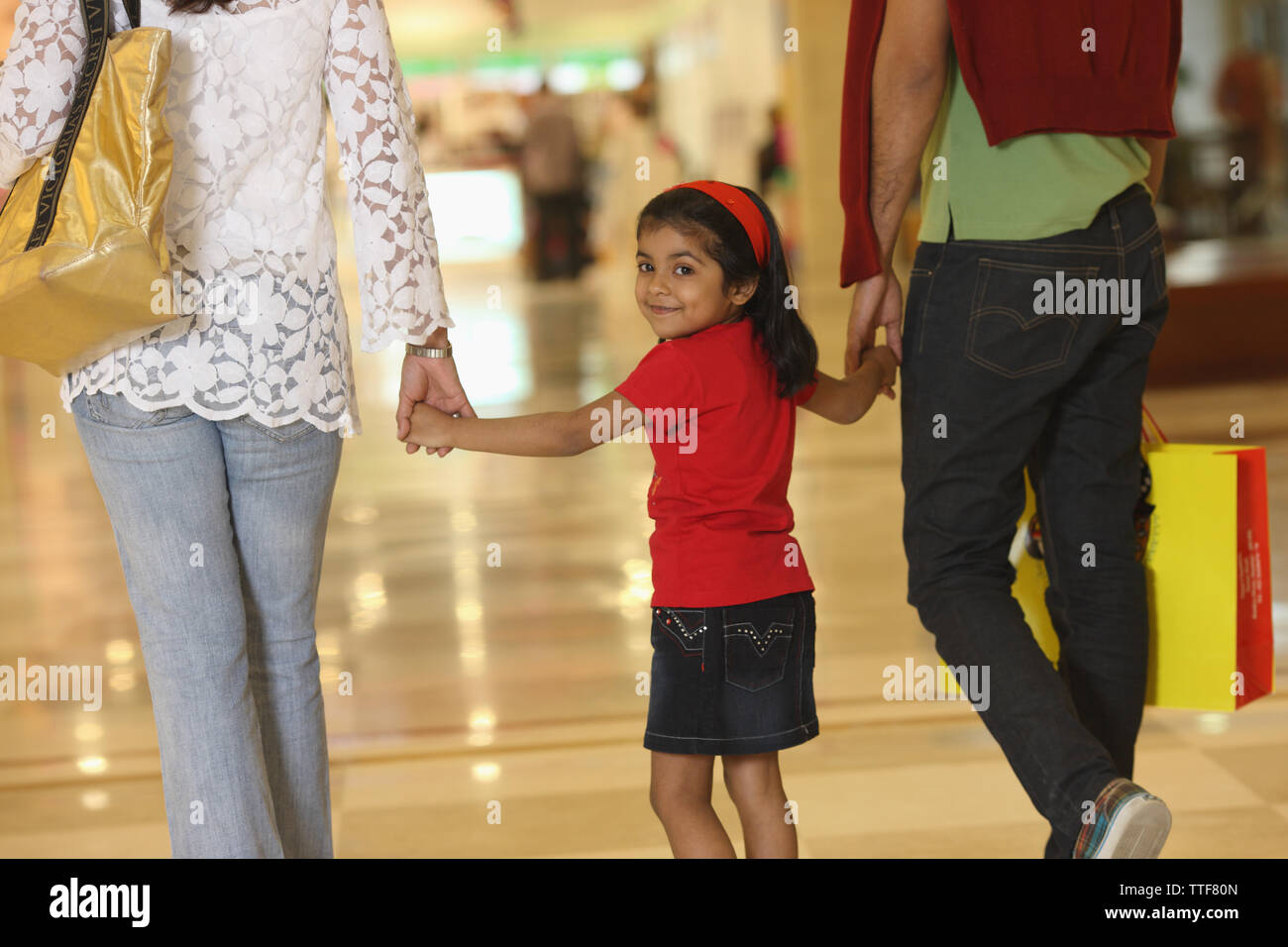 Girl with her parents walking though a shopping mall Stock Photo - Alamy