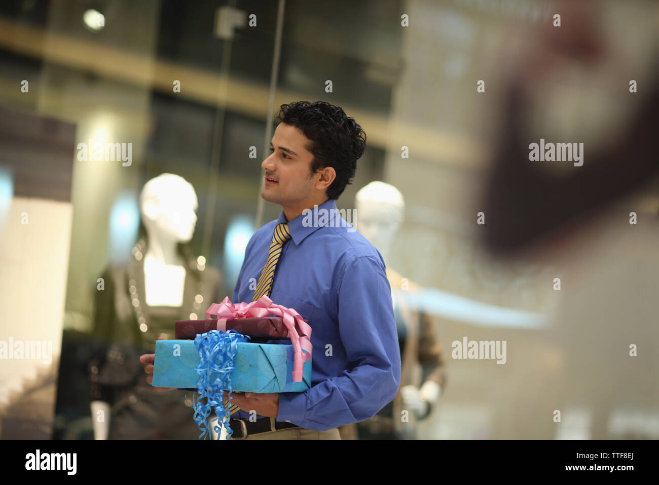 Man holding gifts in a shopping mall Stock Photo - Alamy