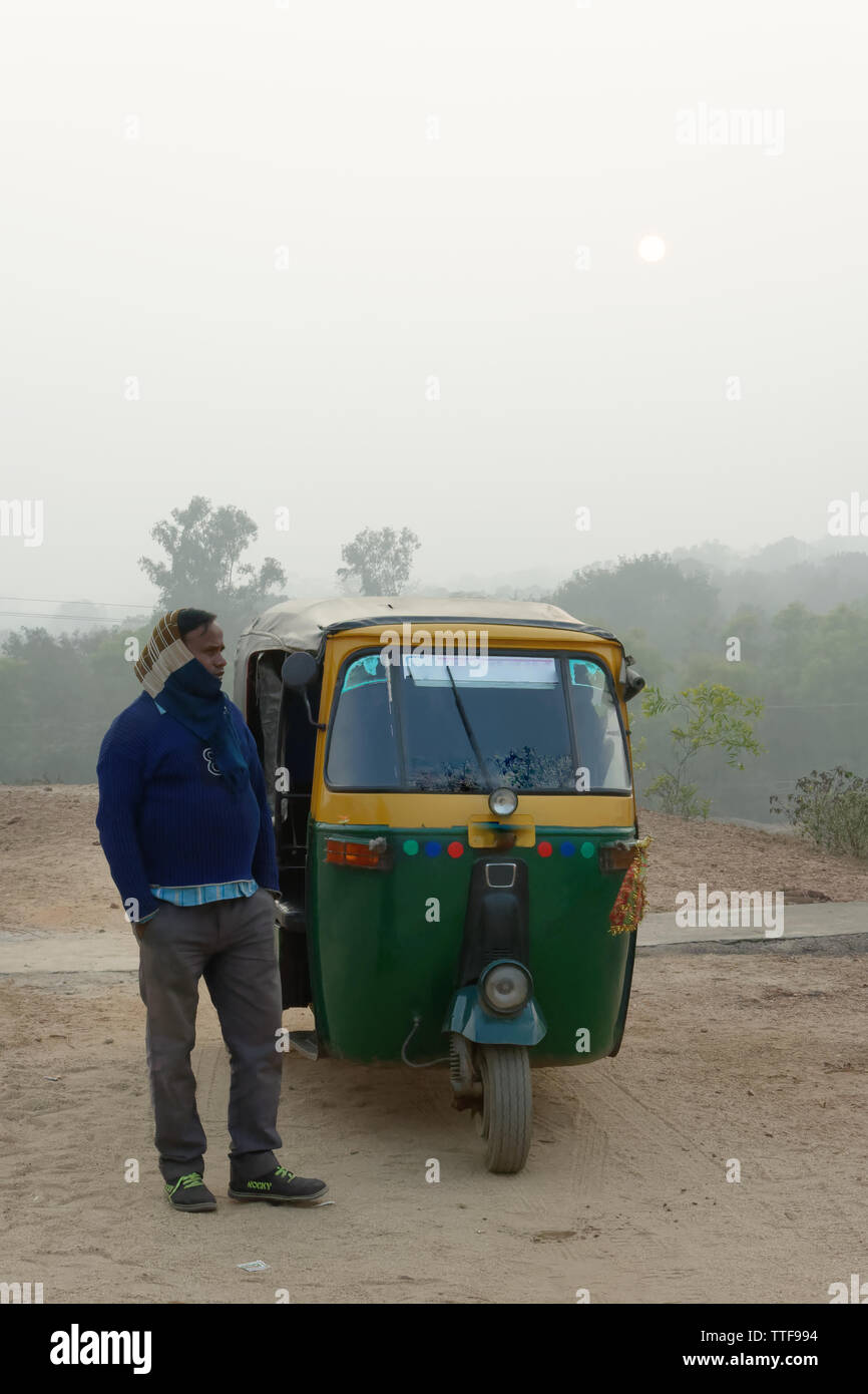 An Indian man is standing beside an Auto rickshaw on a hilltop Stock ...