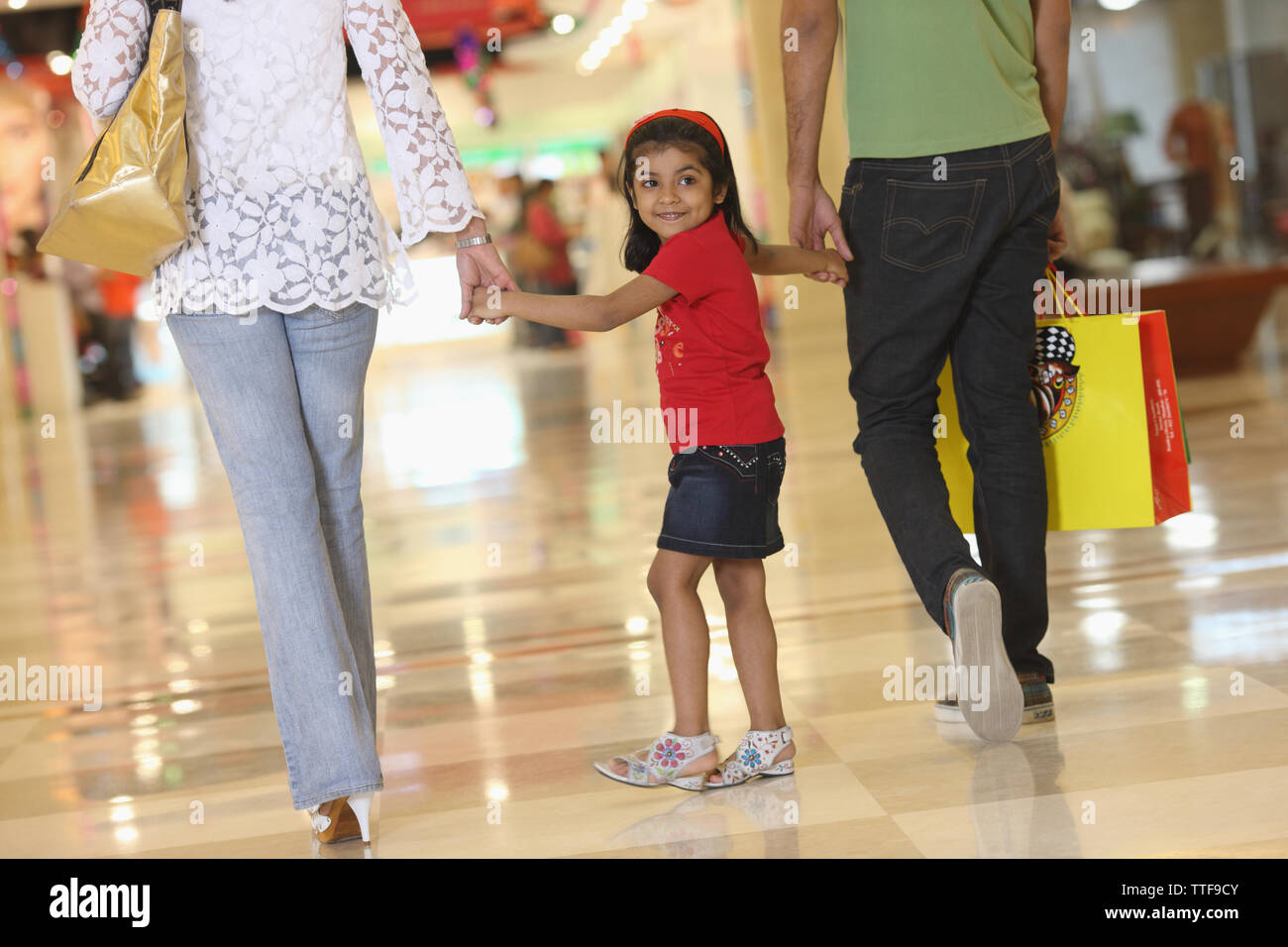 Girl with her parents walking through a shopping mall Stock Photo - Alamy