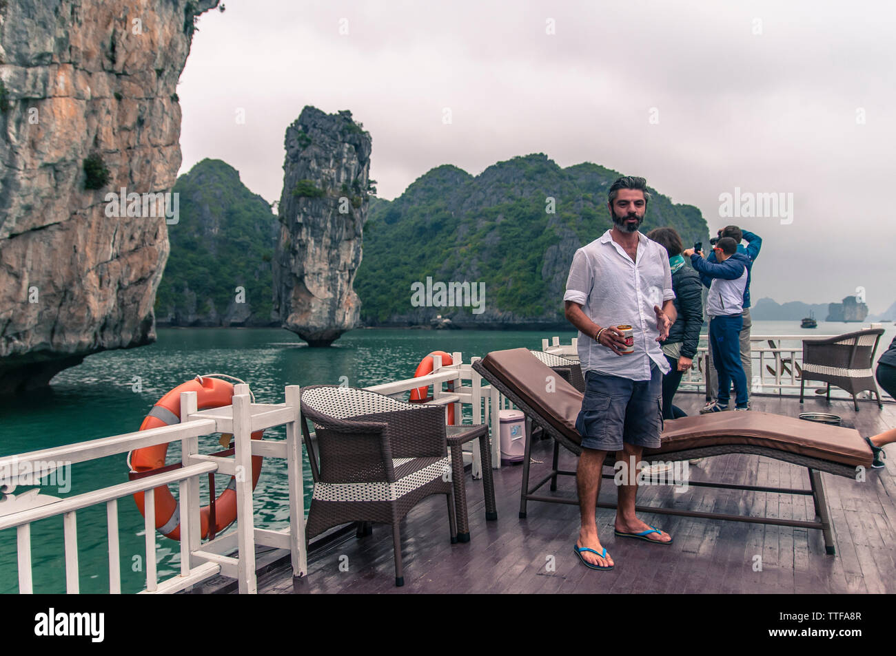 People hanging out on deck of boat while sailing between rock towers ...