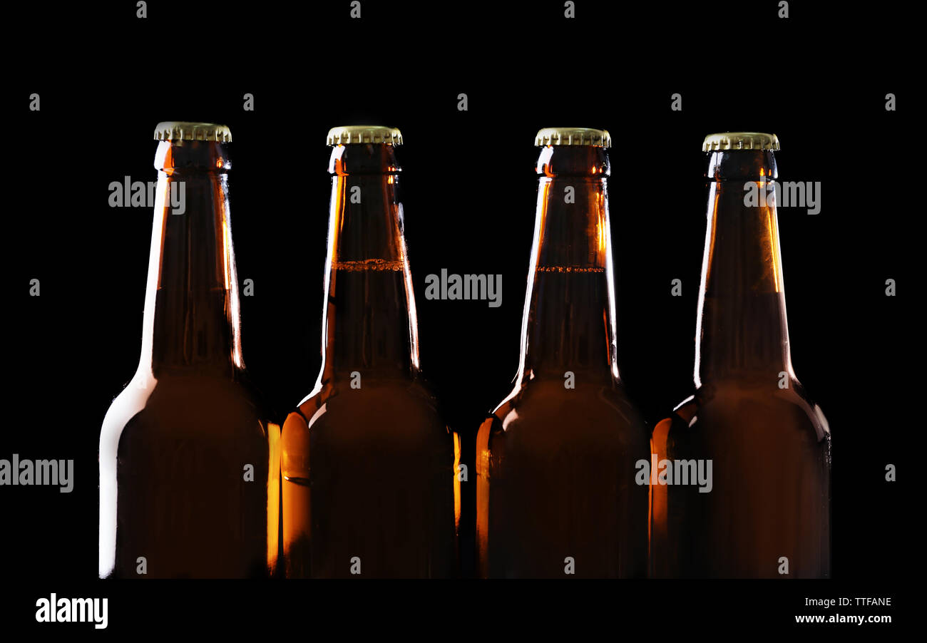 Four bottles of beer on black background Stock Photo - Alamy