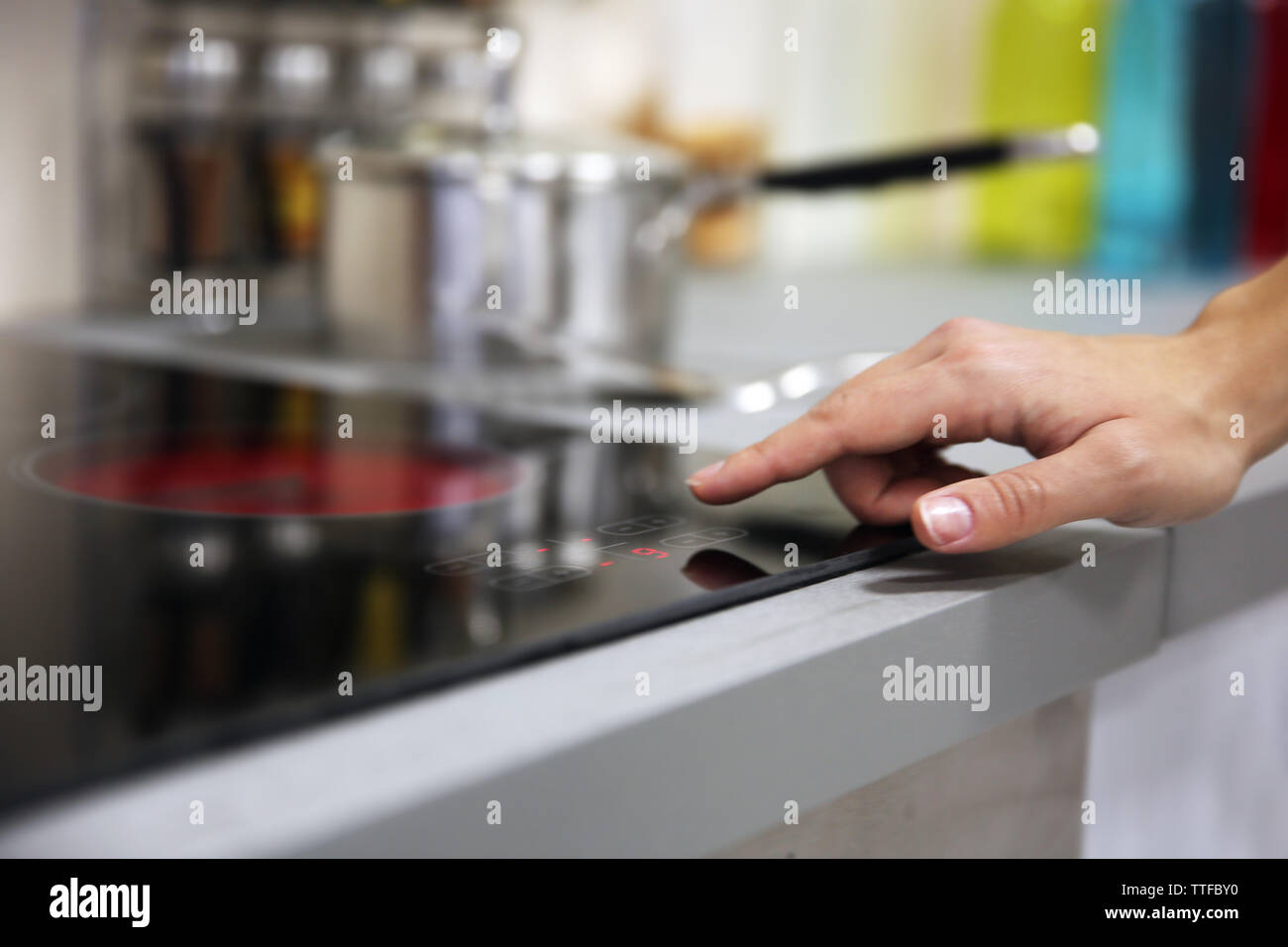Female hand turns on electric hob closeup Stock Photo - Alamy