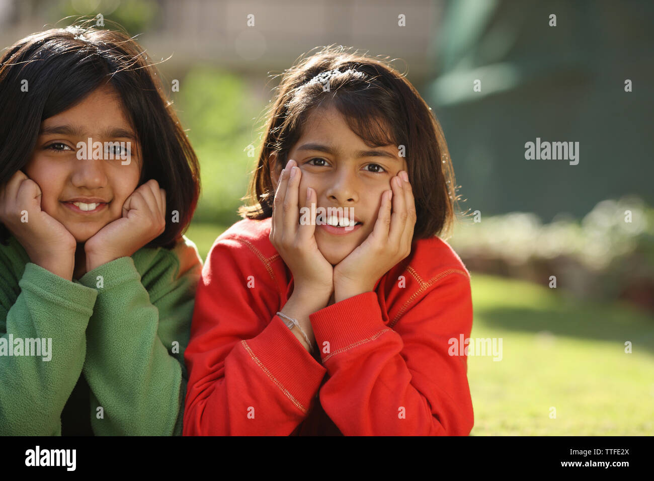 Two girls leaning on elbows and smiling Stock Photo - Alamy