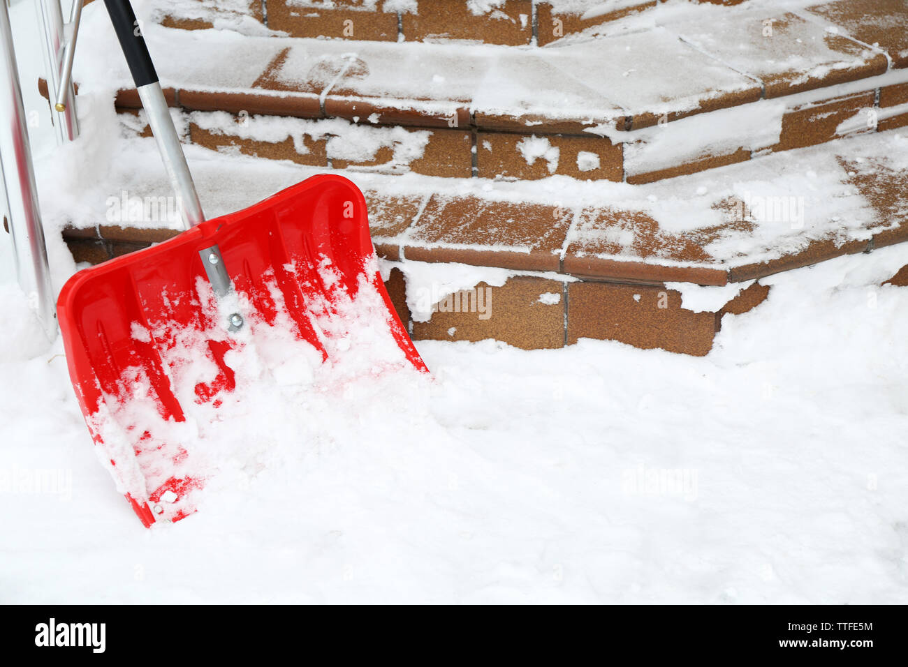 Red shovel for snow removal beside stairs Stock Photo - Alamy