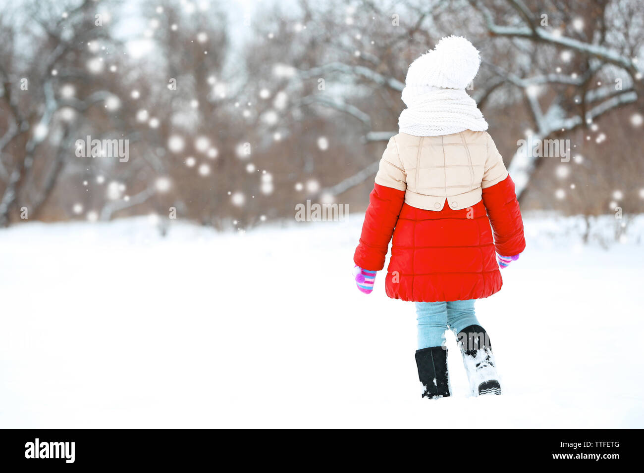 Little girl with winter clothes standing back in snowy park outdoor ...