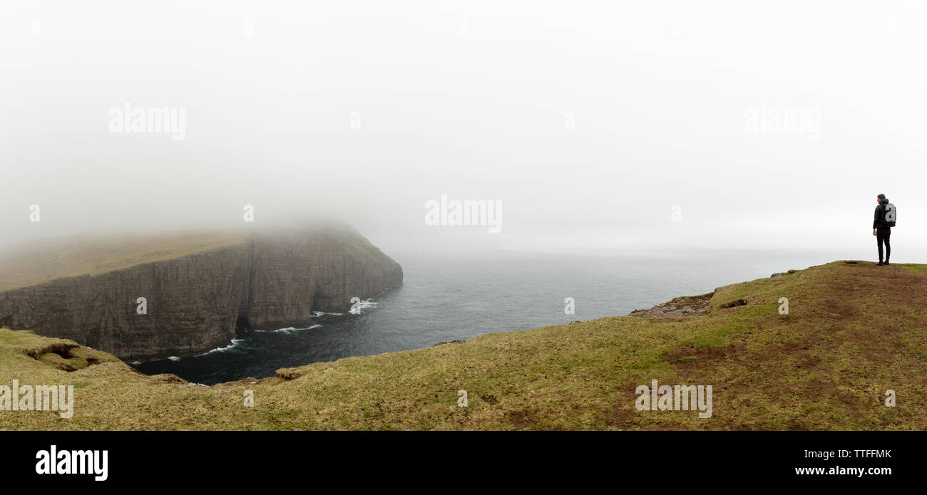 Man standing on edge of cliff with a view Stock Photo - Alamy