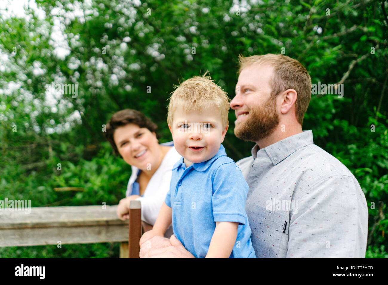 Straight on view of a young boy smiling while standing with his family ...