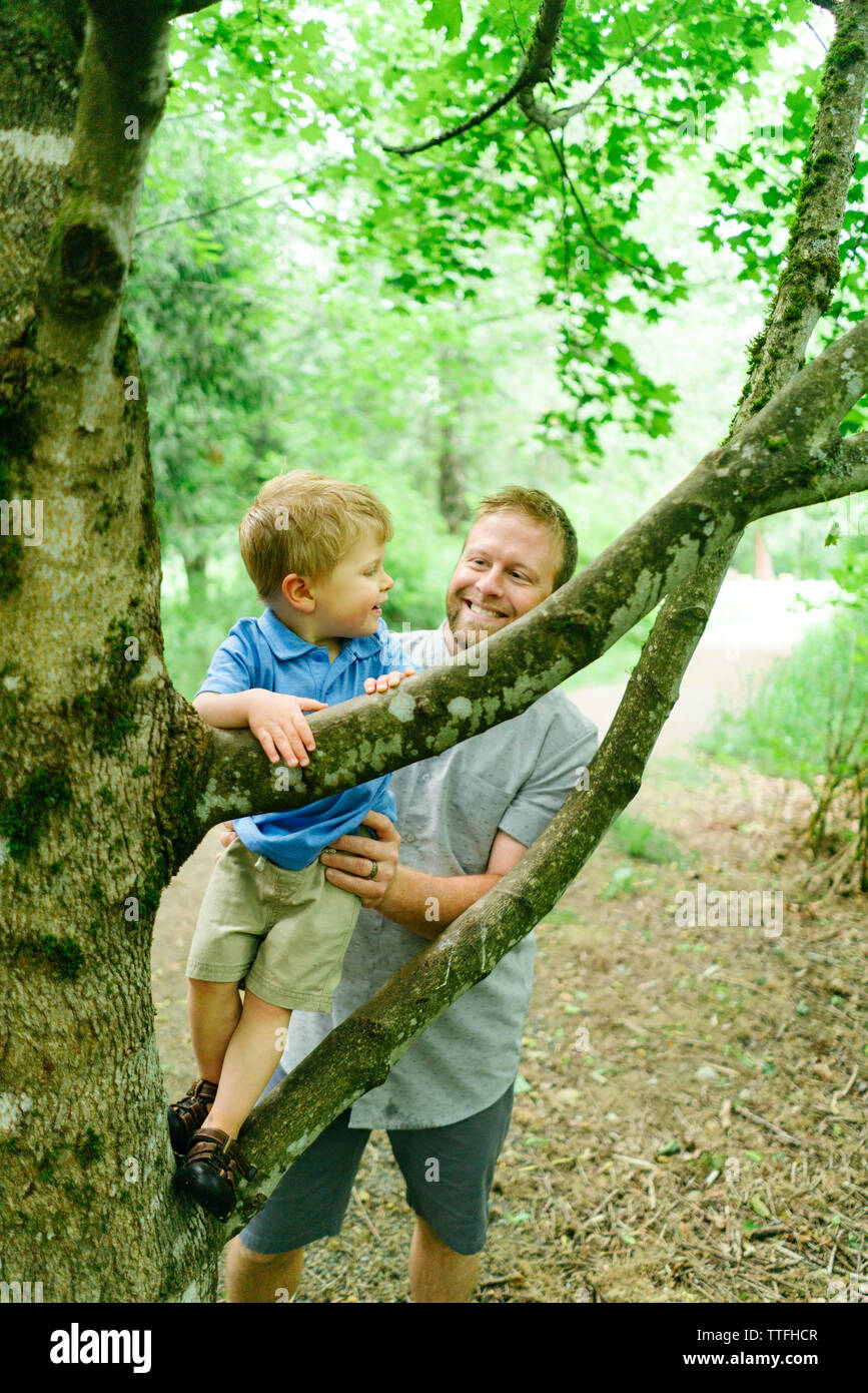 Straight on view of a dad helping his young son climb a tree Stock ...