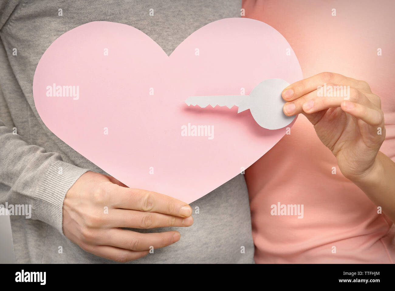 Young couple in love holding paper pink heart and key, close up Stock ...