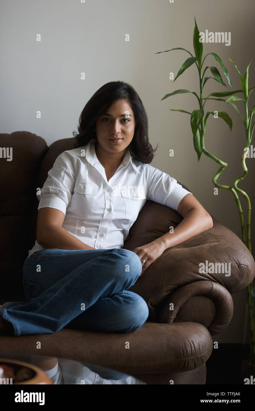 Portrait of a woman sitting on a couch Stock Photo - Alamy