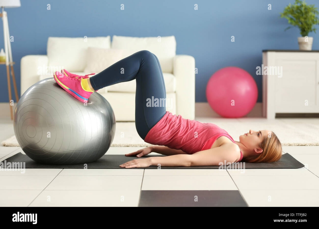 Young sportswoman doing exercises with ball on a mat at home Stock ...
