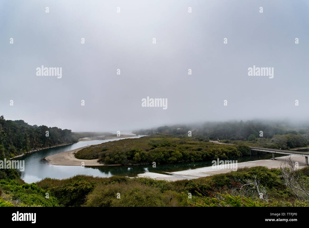 Overview of river bend leading to Pacific ocean through green space ...