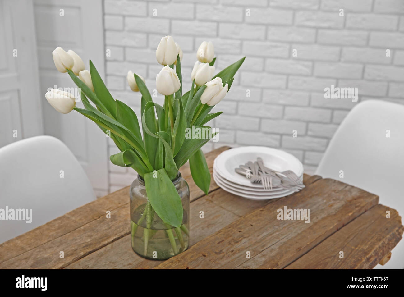 Beautiful bouquet of white tulips flowers and utensils on wooden table ...