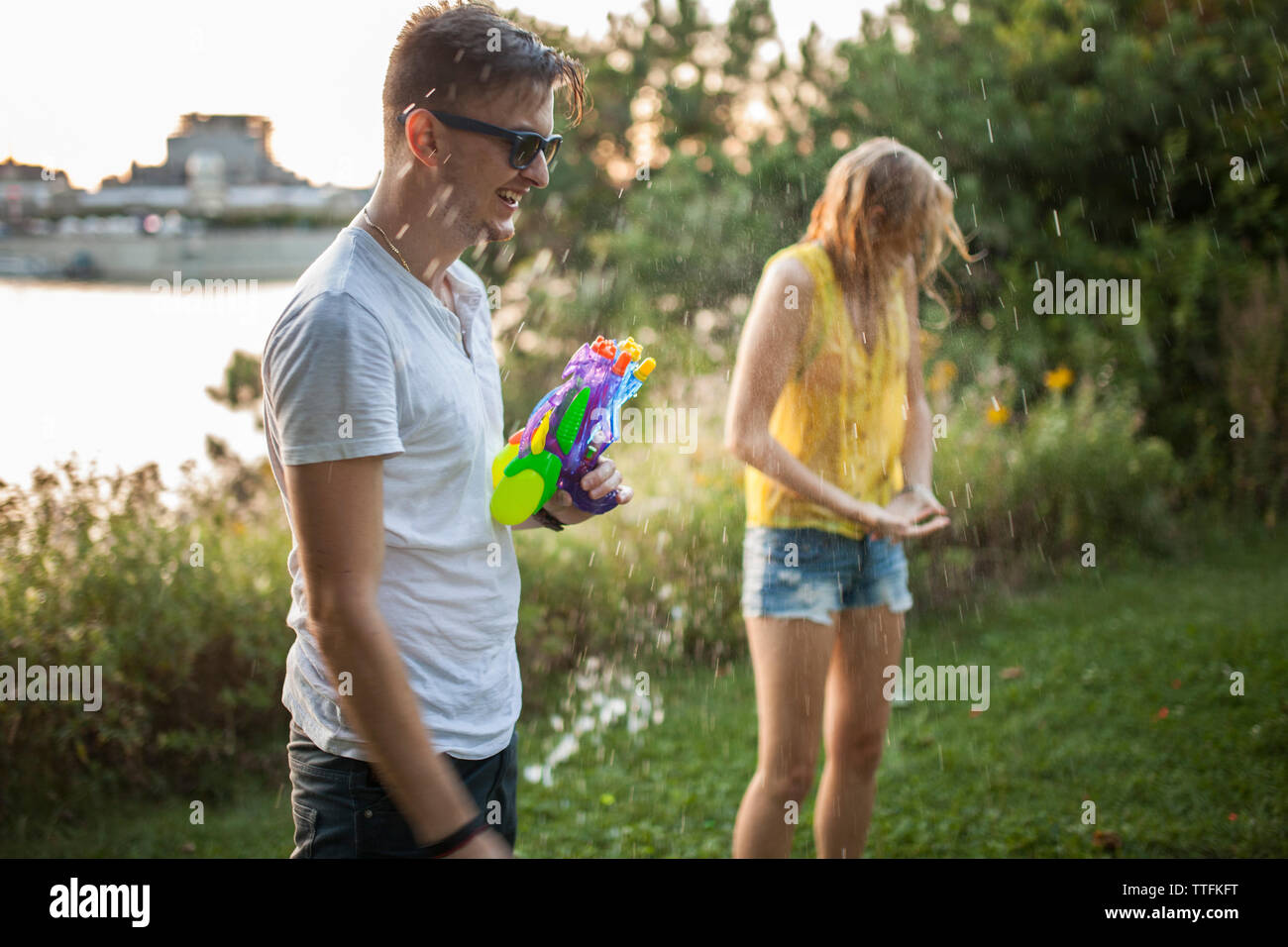 Friends throwing water balloons at eachother laughing hysterically ...