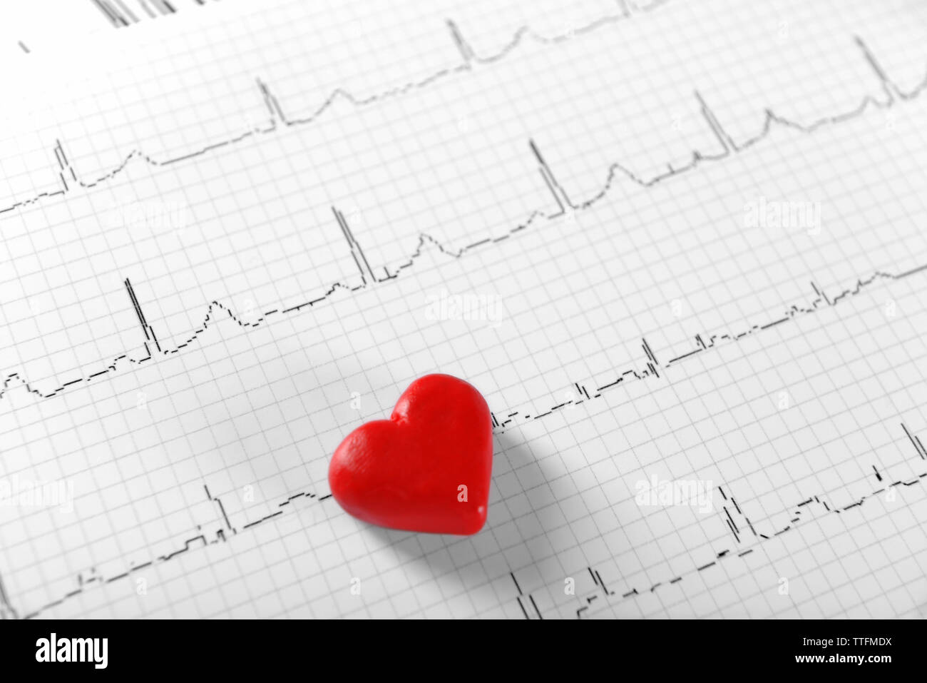 Cardiogram chart with small red heart on table closeup Stock Photo - Alamy