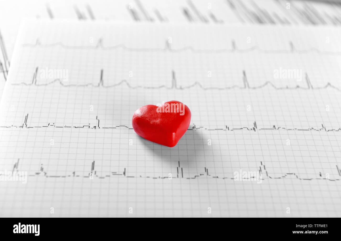 Cardiogram chart with small red heart on table closeup Stock Photo - Alamy