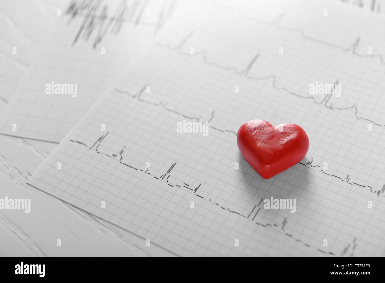 Cardiogram chart with small red heart on table closeup Stock Photo - Alamy