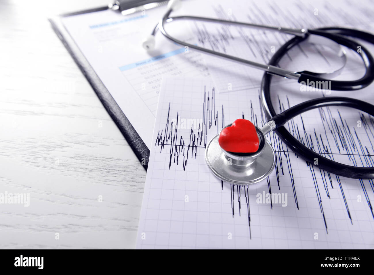 Cardiogram chart with medical stethoscope and small red heart on table ...