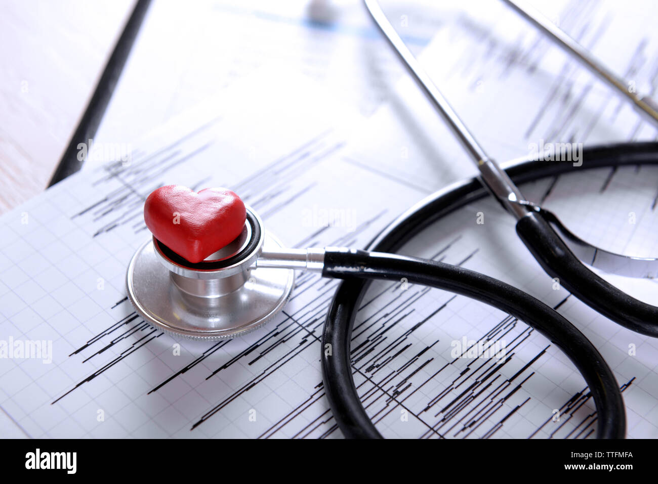 Cardiogram chart with medical stethoscope and small red heart on table ...