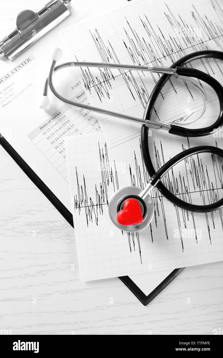 Cardiogram chart with medical stethoscope and small red heart on table ...