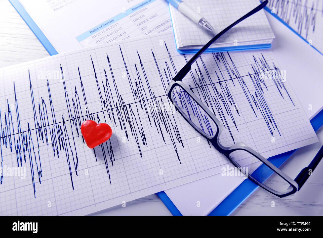 Cardiogram chart with glasses and small red heart on table closeup ...