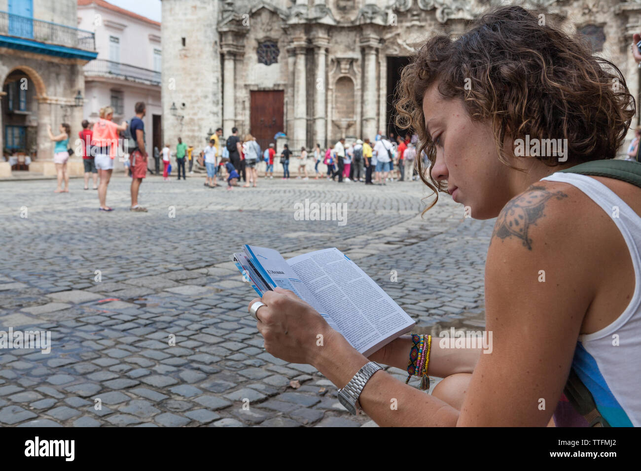 Western girl reading a travel guide in the historical old Havana, Cuba ...