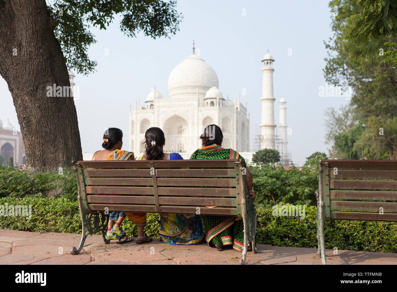 3 Indian women sitting on a bench watching the Taj Mahal temple, Agra ...
