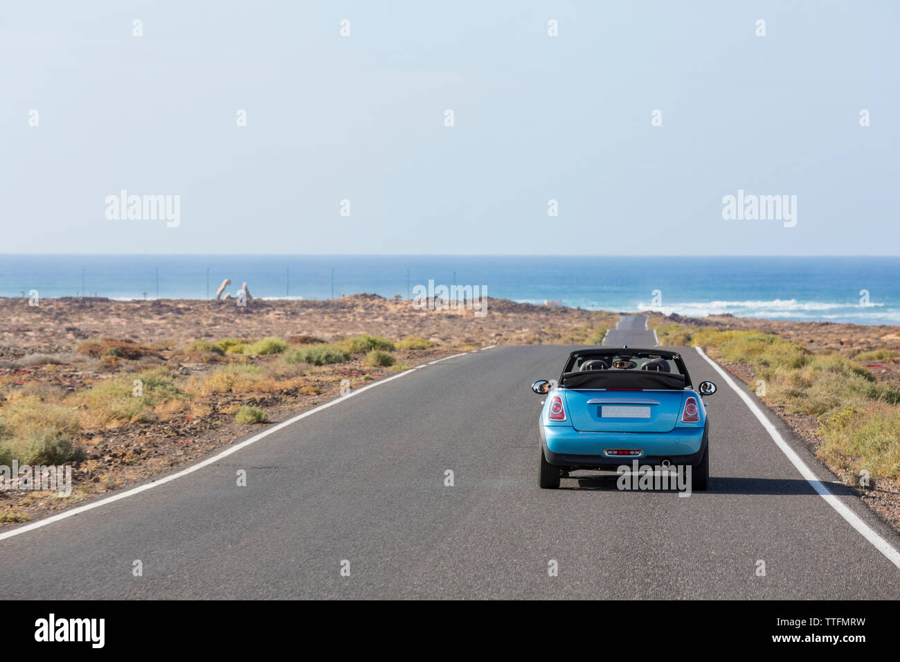 Blue cabrio car driving in empty paved road towards the ocean Stock ...