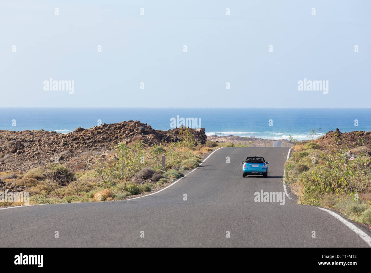 Blue cabrio car driving in empty paved road towards the ocean Stock ...