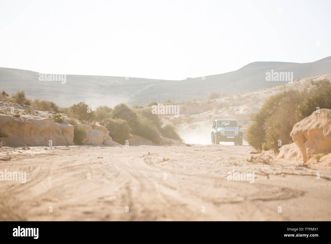 White jeep 4x4 driving off road a empty dusty and sandy dirty road ...