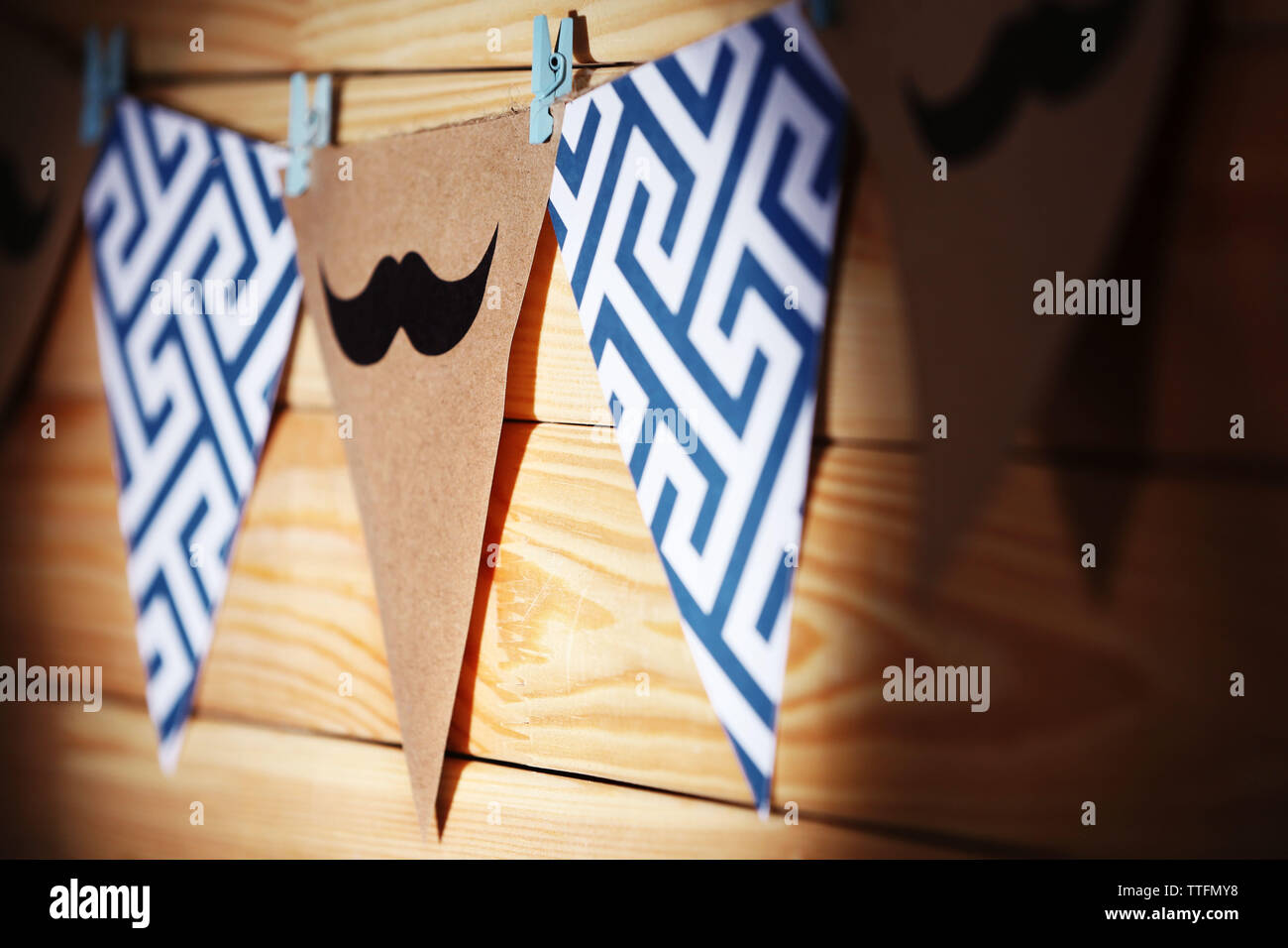 Hanging flags with mustaches on wooden background Stock Photo - Alamy