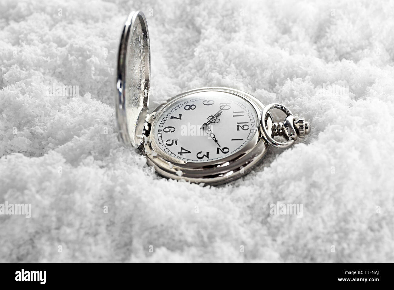 Pocket watch over white snow background Stock Photo - Alamy