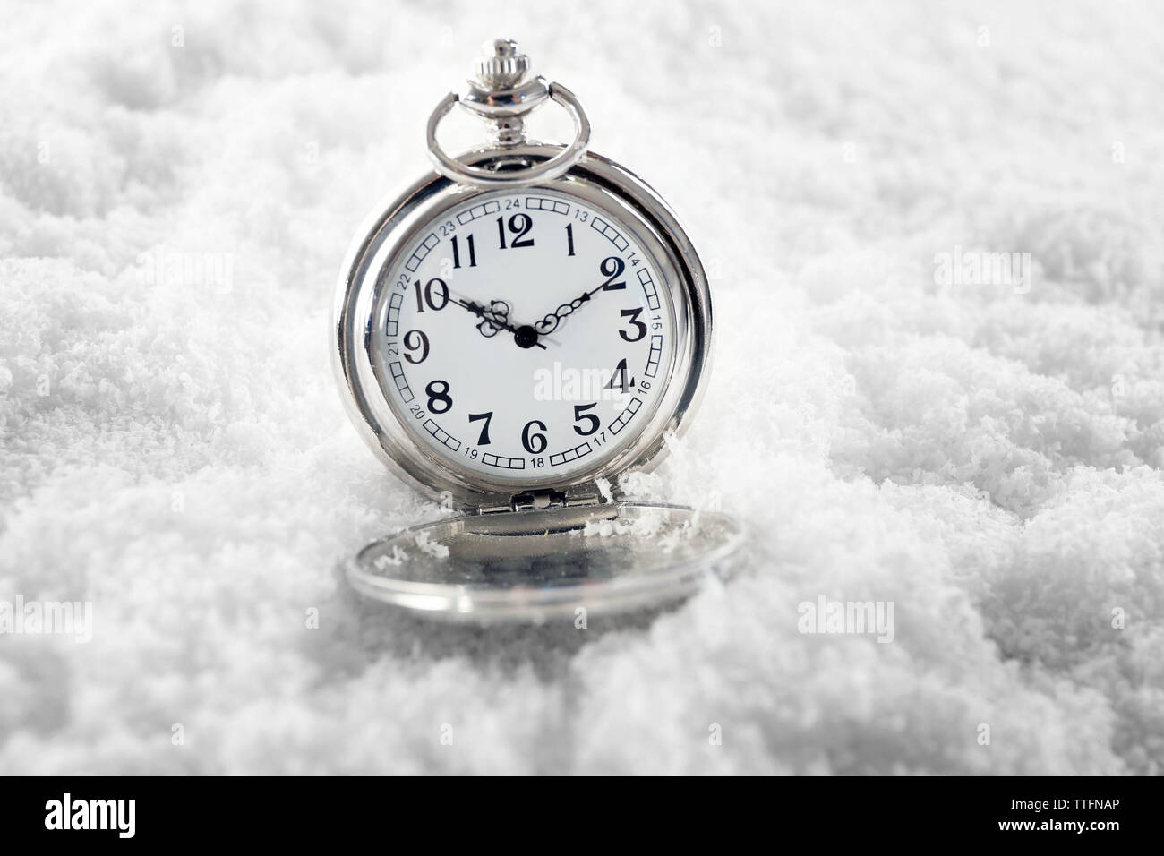 Pocket watch over white snow background Stock Photo - Alamy
