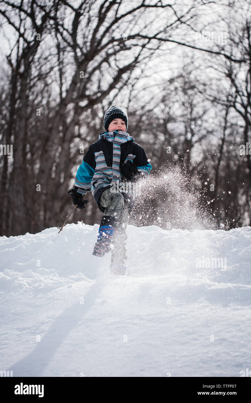 Young boy kicking snow in air on a winter day in wooded area Stock ...