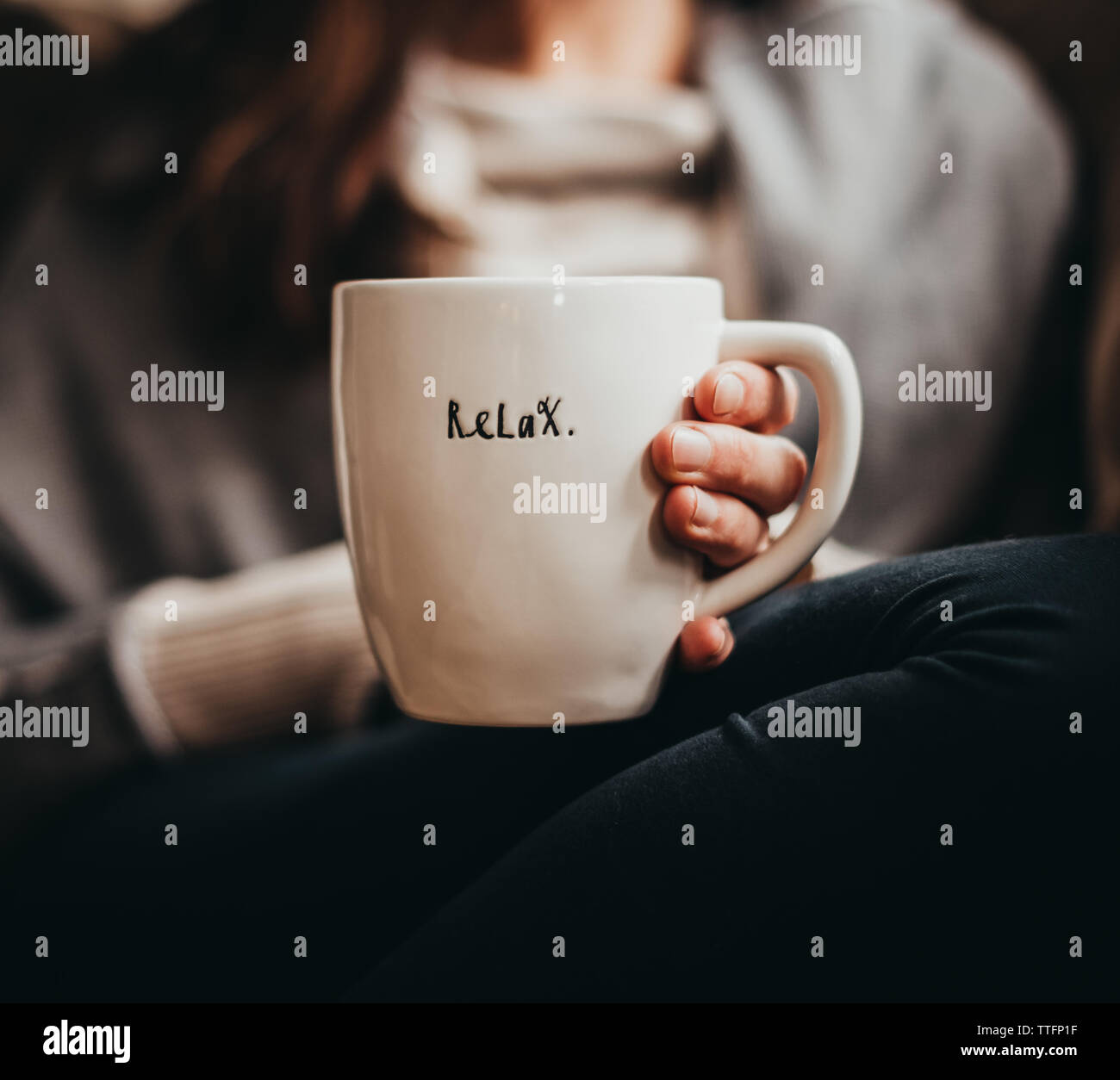 Close up of hand holding white mug with word relax written on it Stock ...
