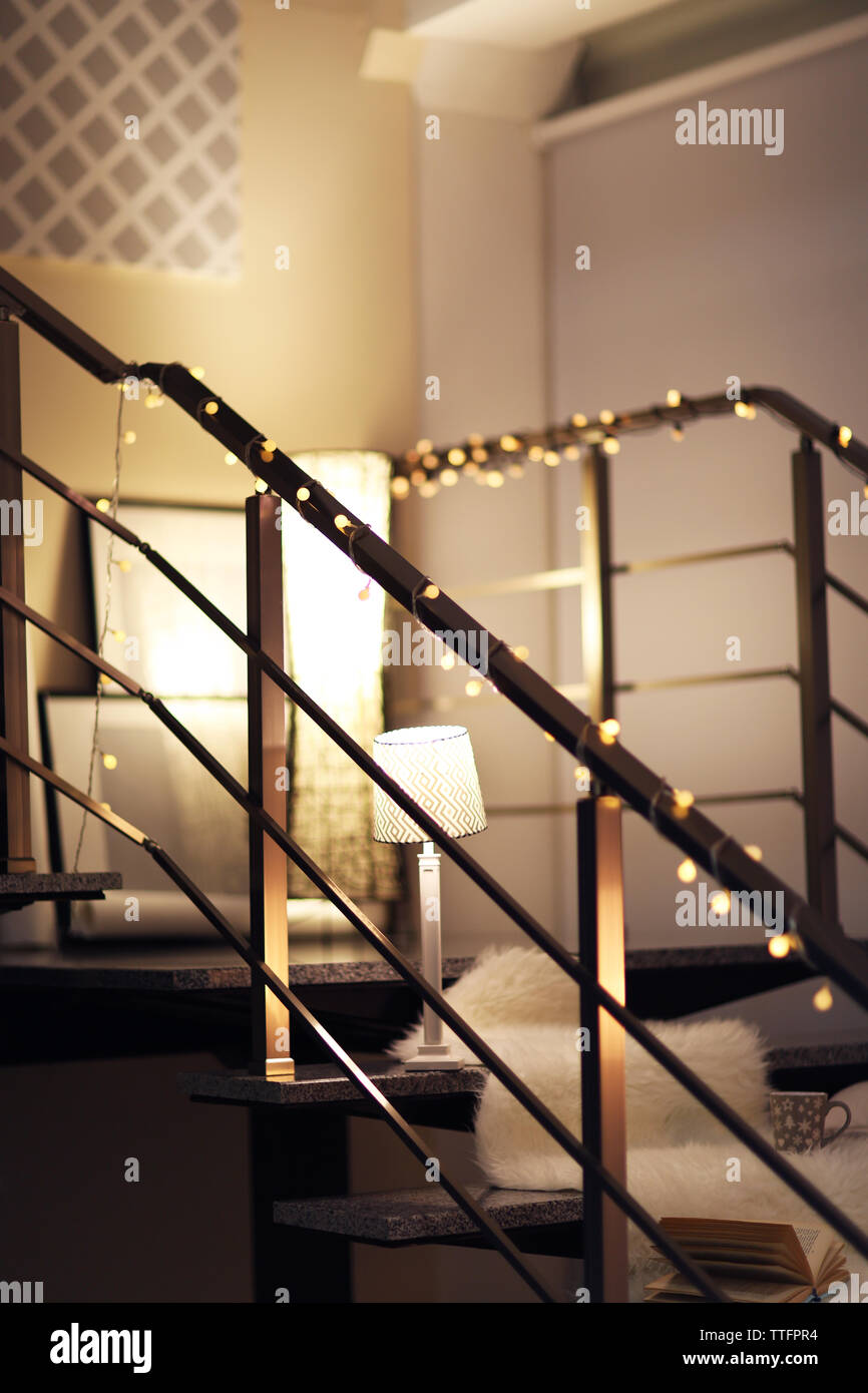 Resting-place with electric garland, cup of tea, book and lamps on ...