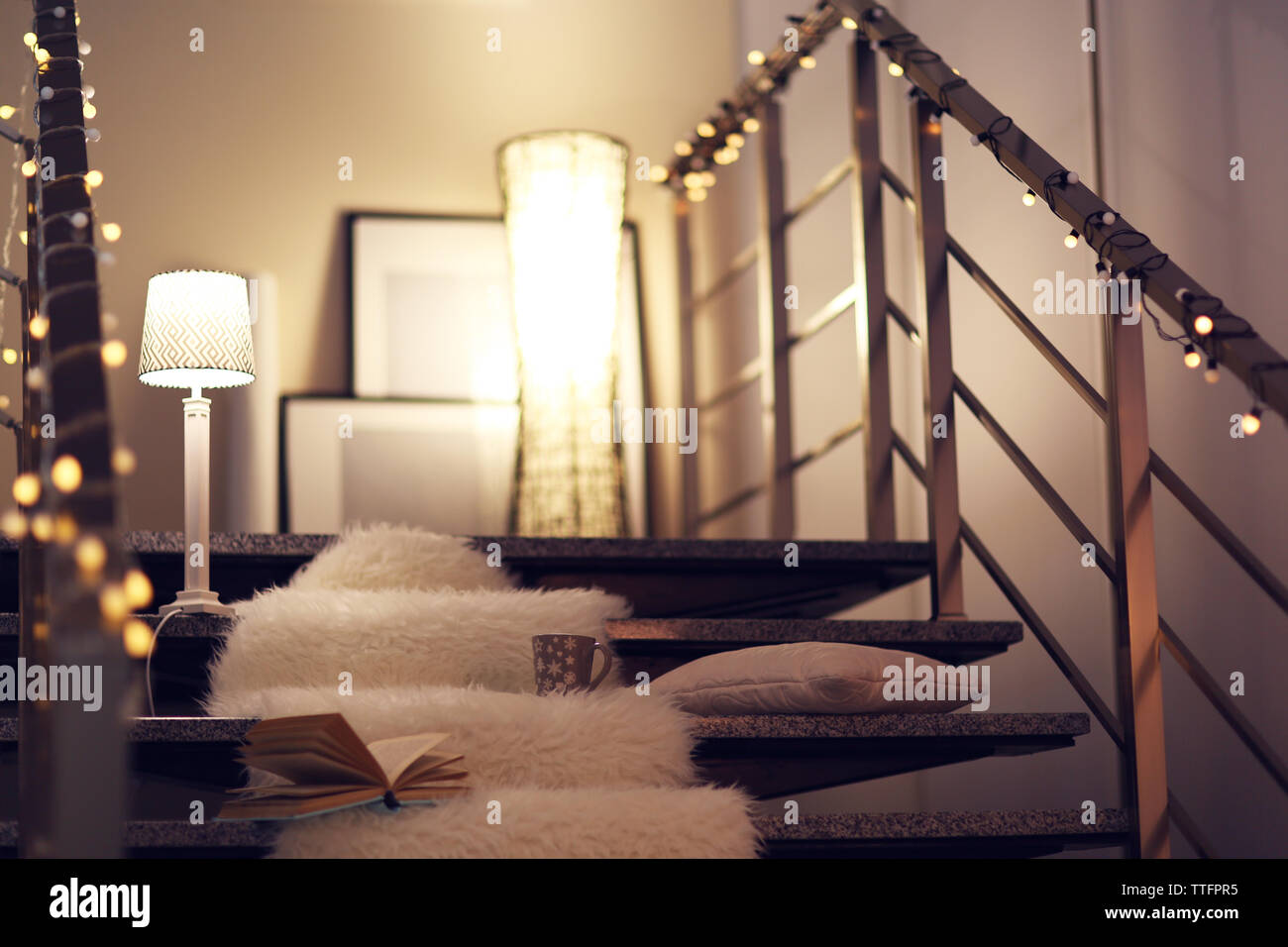 Resting-place with electric garland, cup of tea, book and lamps on ...