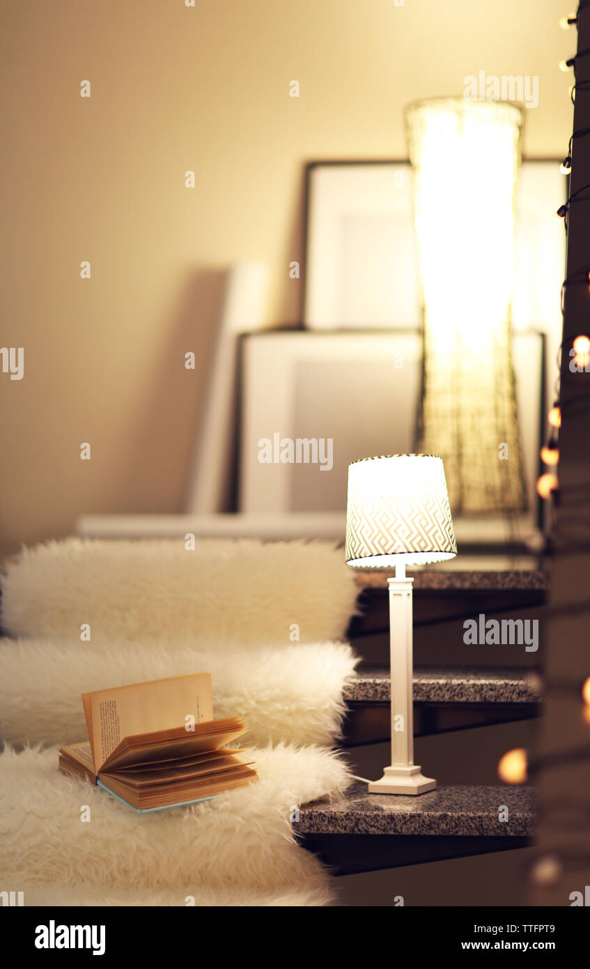 Resting-place with electric garland, book and lamps on modern stairs ...
