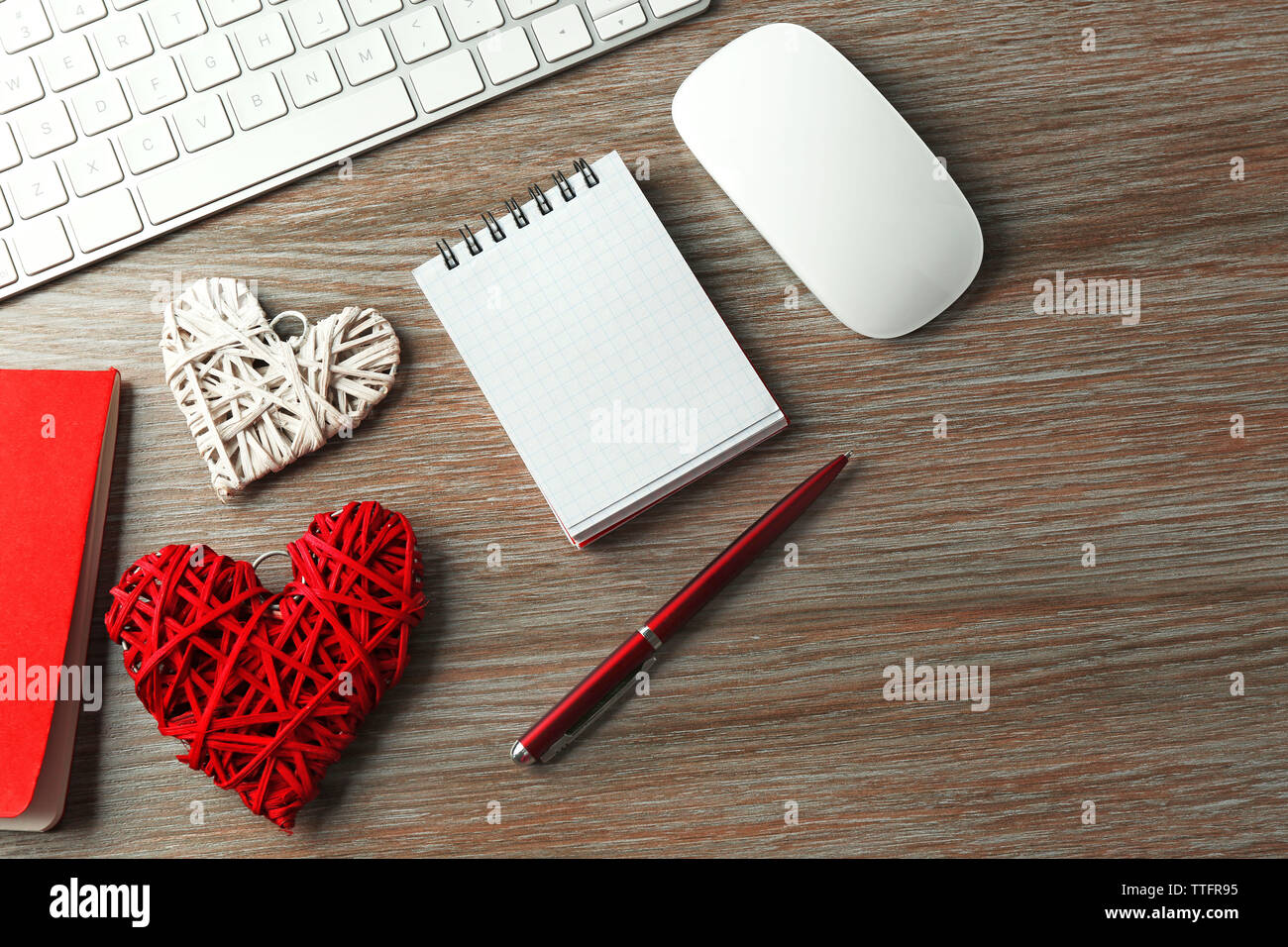 Computer peripherals with hearts, pen and notebooks on wooden table ...