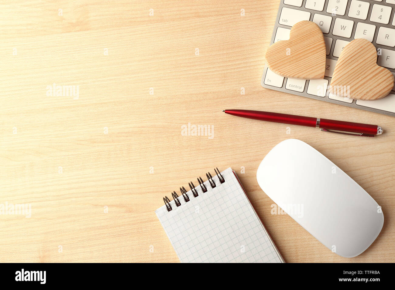 Computer peripherals with wooden hearts, pen and notebook on light ...