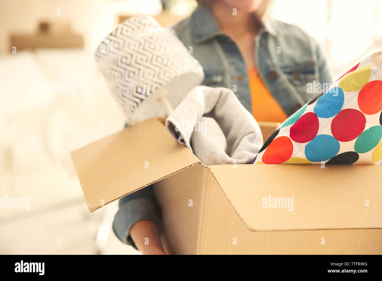 Young woman holding open cardboard box with things for moving into new ...