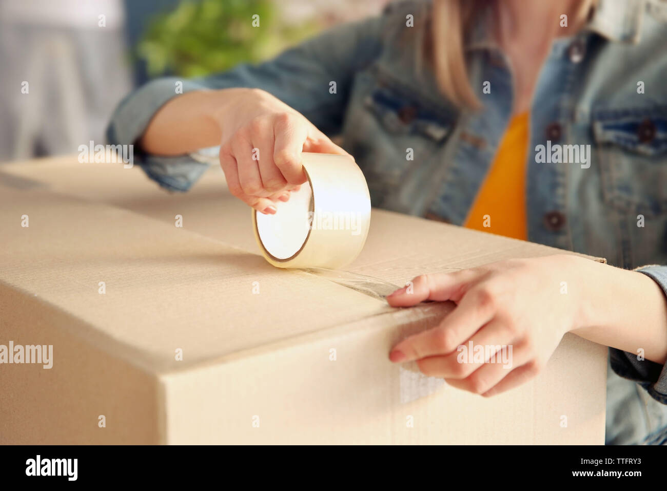 Young girl sealing with tape big cardboard box for moving Stock Photo ...