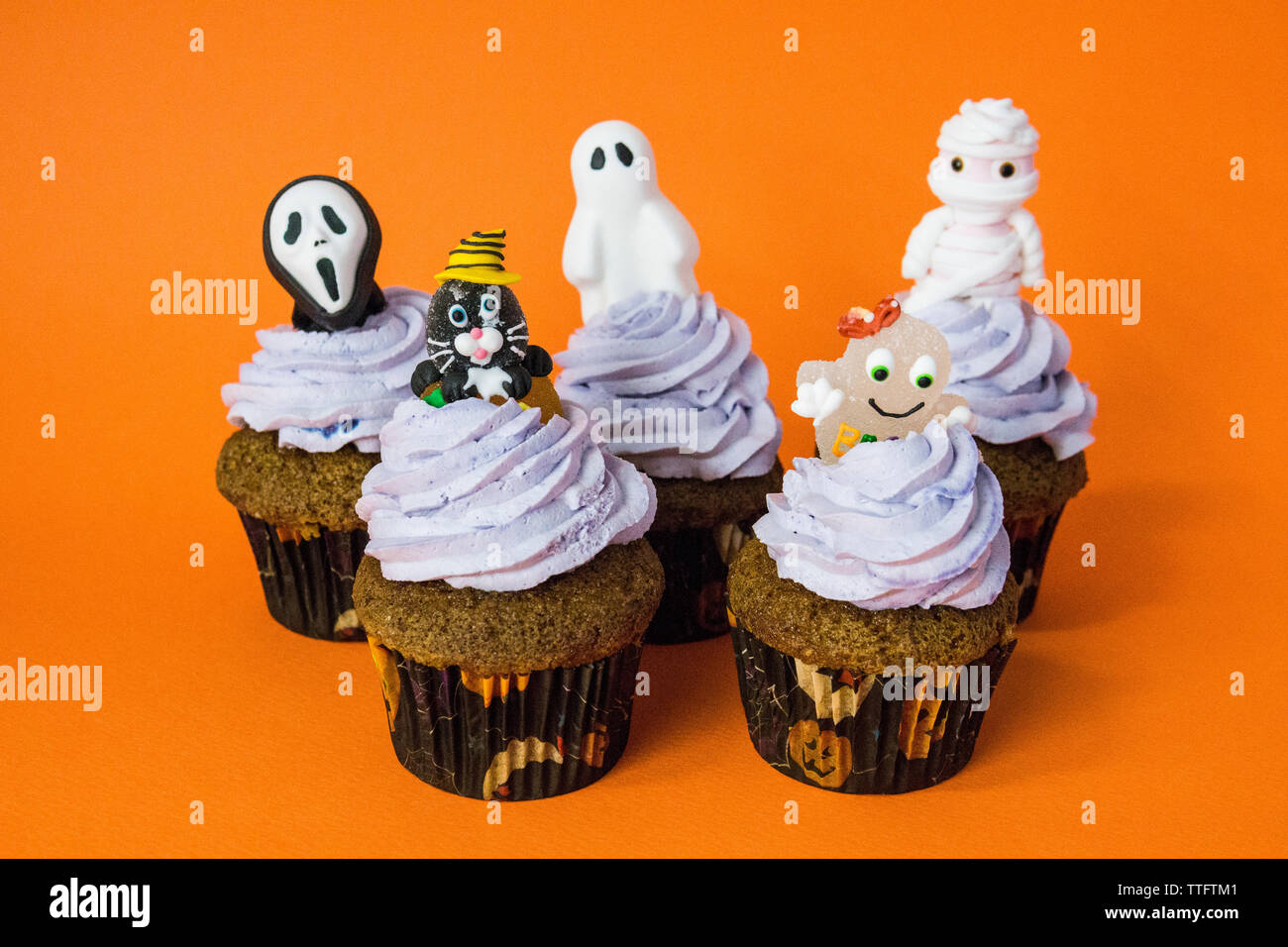 group of funny halloween monster cupcakes on an orange table Stock ...