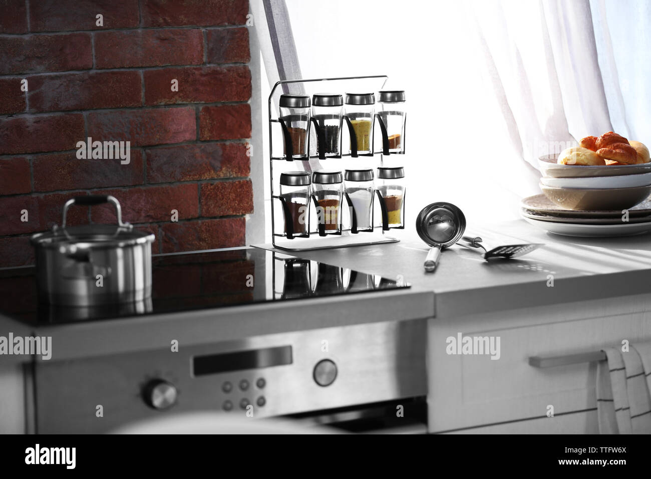 Modern kitchen table with electric stove and utensils beside the window ...
