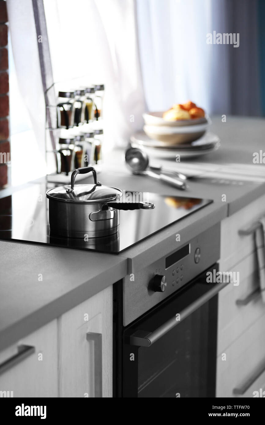 Modern kitchen table with electric stove and utensils beside the window ...