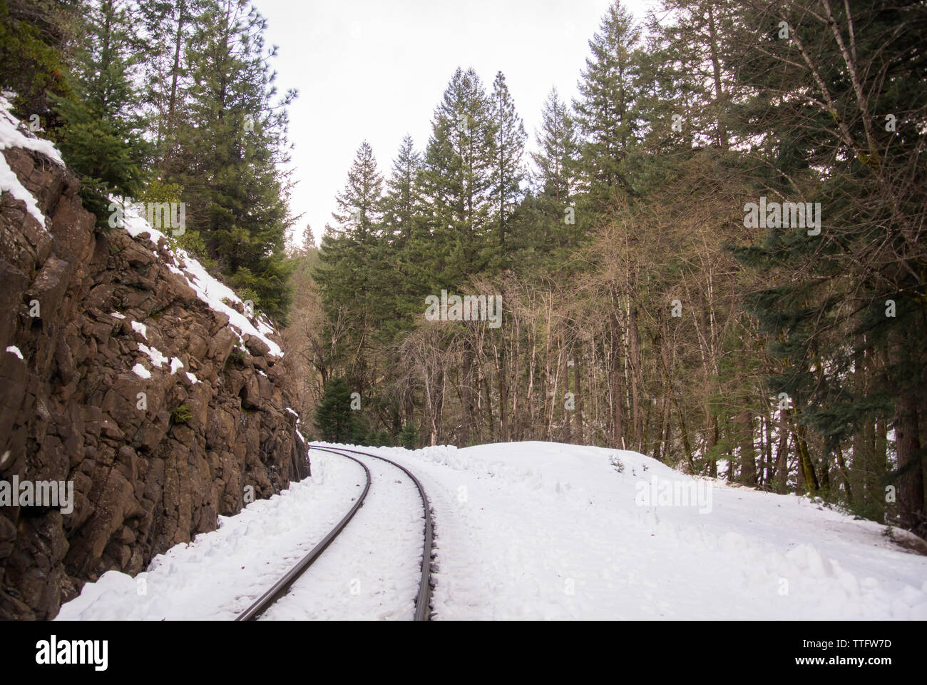Railroad tracks through a snow covered rocky forest landscape Stock ...