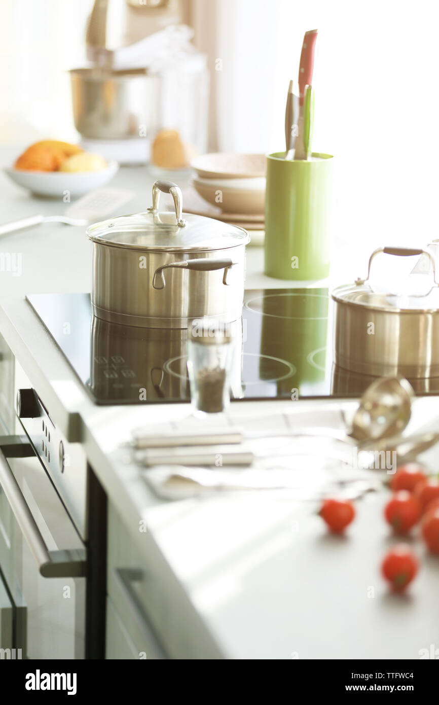 Modern table and electric stove with utensils and vegetables in the ...